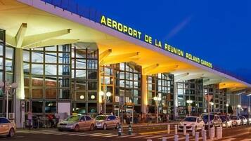 Um terminal de aeroporto com uma grande fachada de vidro e uma placa com a inscrição 'AEROPORT DE LA REUNION ROLAND GARROS'.