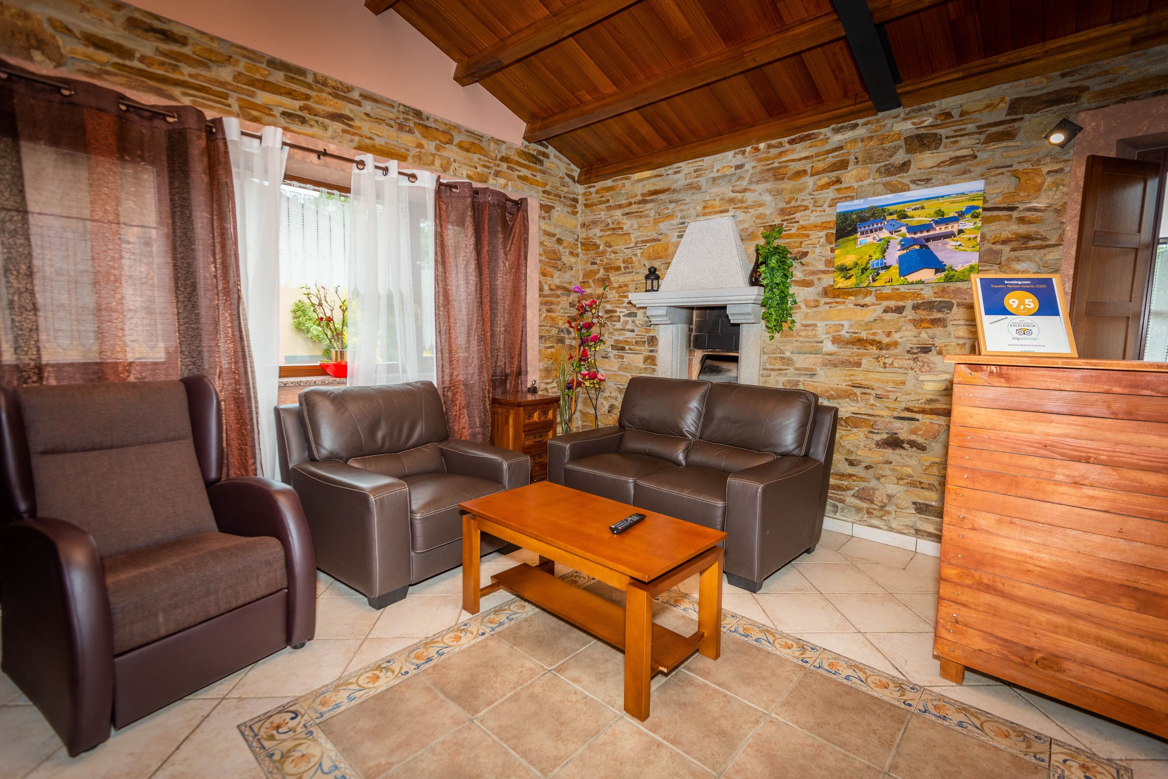 Uma sala de estar com paredes de pedra, lareira, sofás de couro e mesa de centro de madeira.