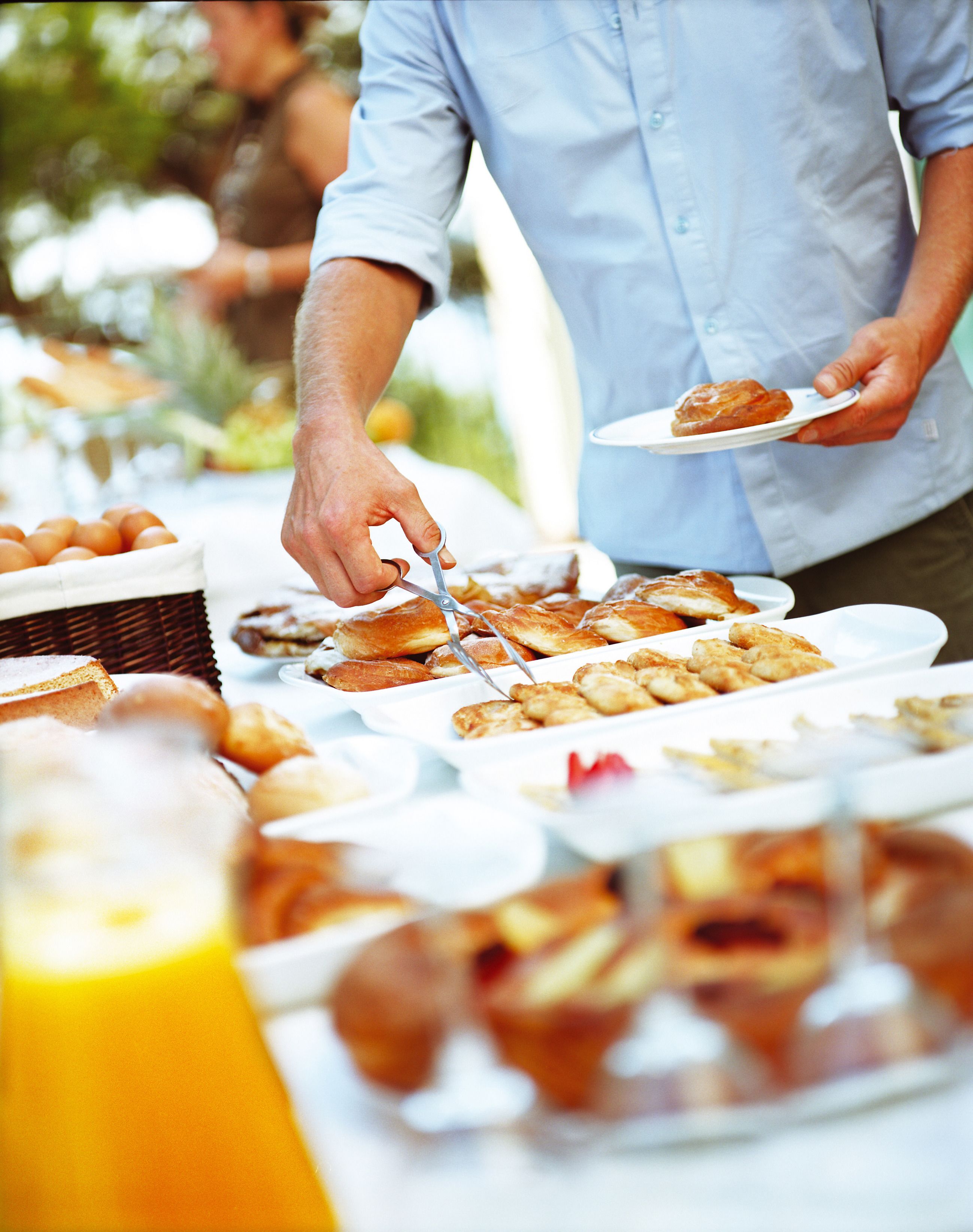 Buffet com diversos alimentos e uma pessoa se servindo.