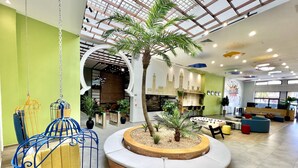 Um hall amplo com área de estar central, balcão de recepção e teto alto com claraboias.