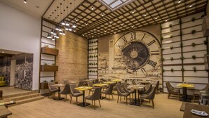 Restaurante moderno com um relógio de parede grande, mesas e cadeiras de madeira.