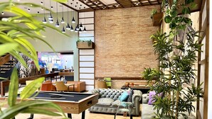 Uma área de estar moderna com mesa de bilhar, sofás de couro e luminárias pendentes.