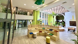 Um interior moderno com área de estar central, teto alto com iluminação embutida e vista para o exterior.