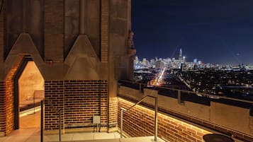 Vista noturna de um ponto alto com vista para a cidade iluminada e um rio.