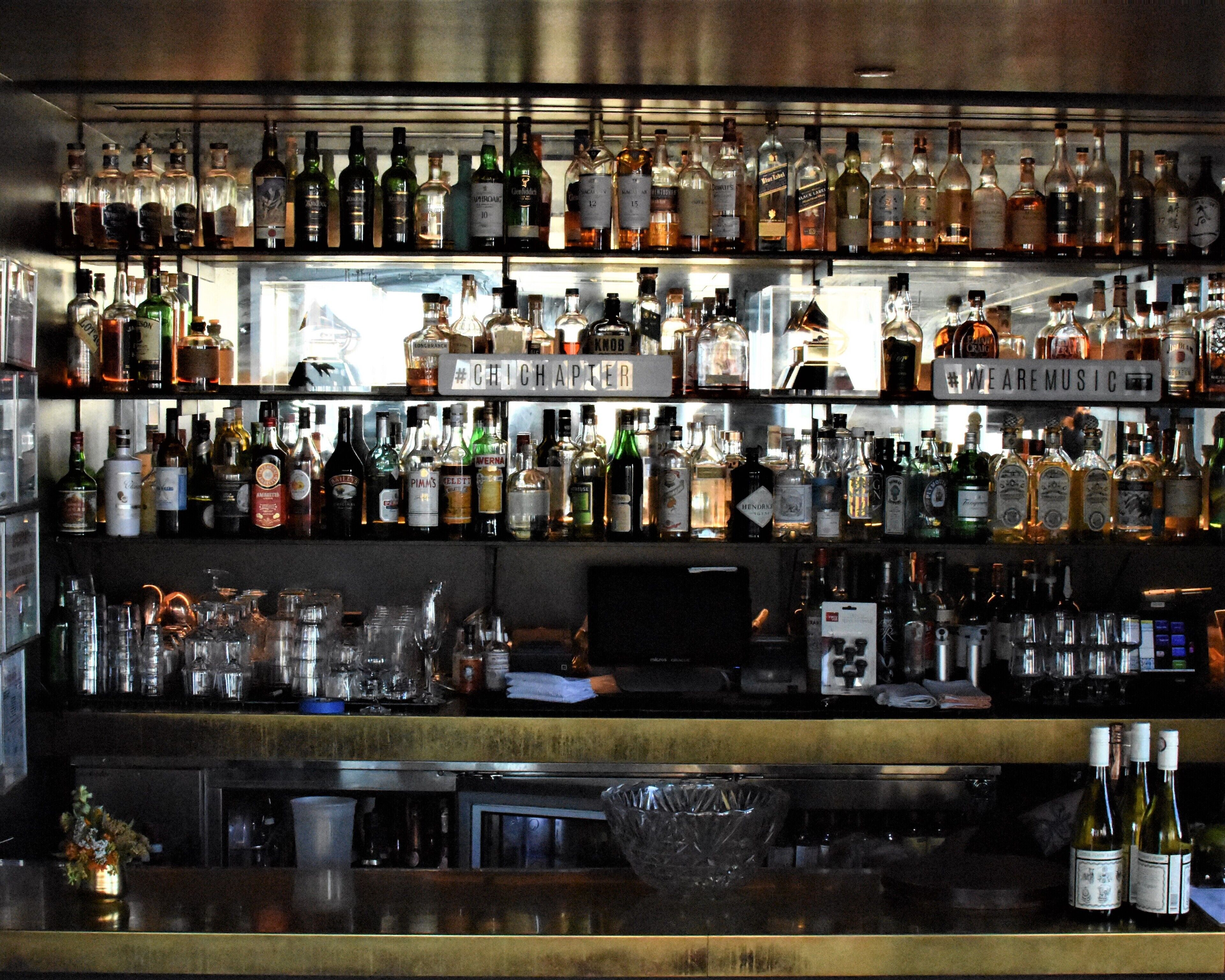 Um bar com várias prateleiras repletas de garrafas de bebidas.
