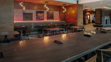 Um restaurante moderno com uma longa mesa comunitária, cabines e luminárias pendentes.