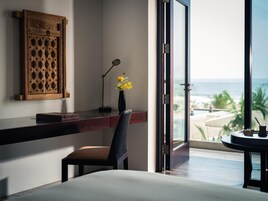 Quarto moderno com escrivaninha, cadeira e vista para o oceano.