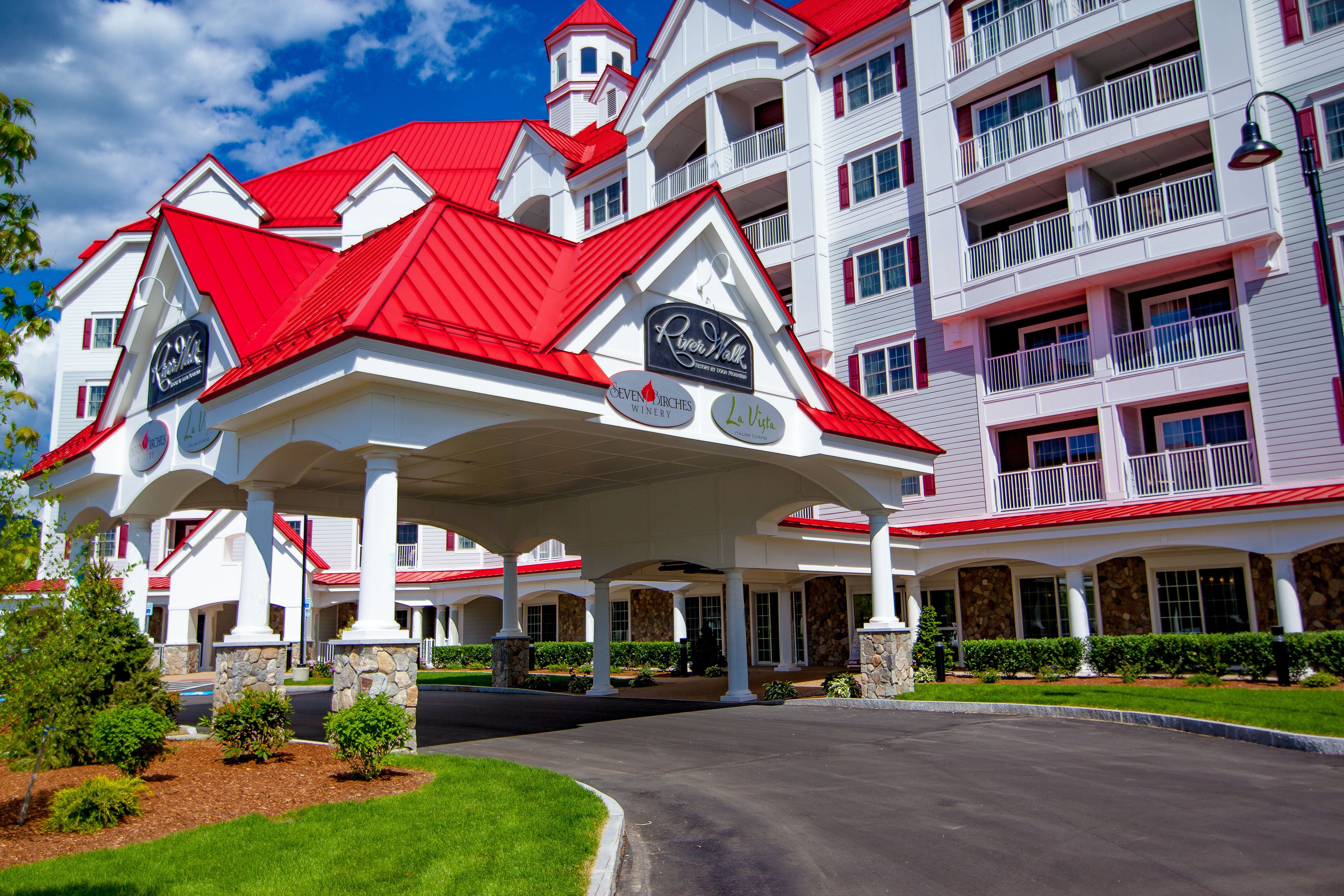 Um hotel com telhado vermelho, colunas brancas e fachada de pedra.
