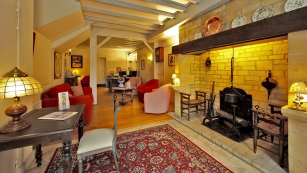 Uma sala de estar acolhedora com lareira, móveis vermelhos e brancos e piso de madeira.