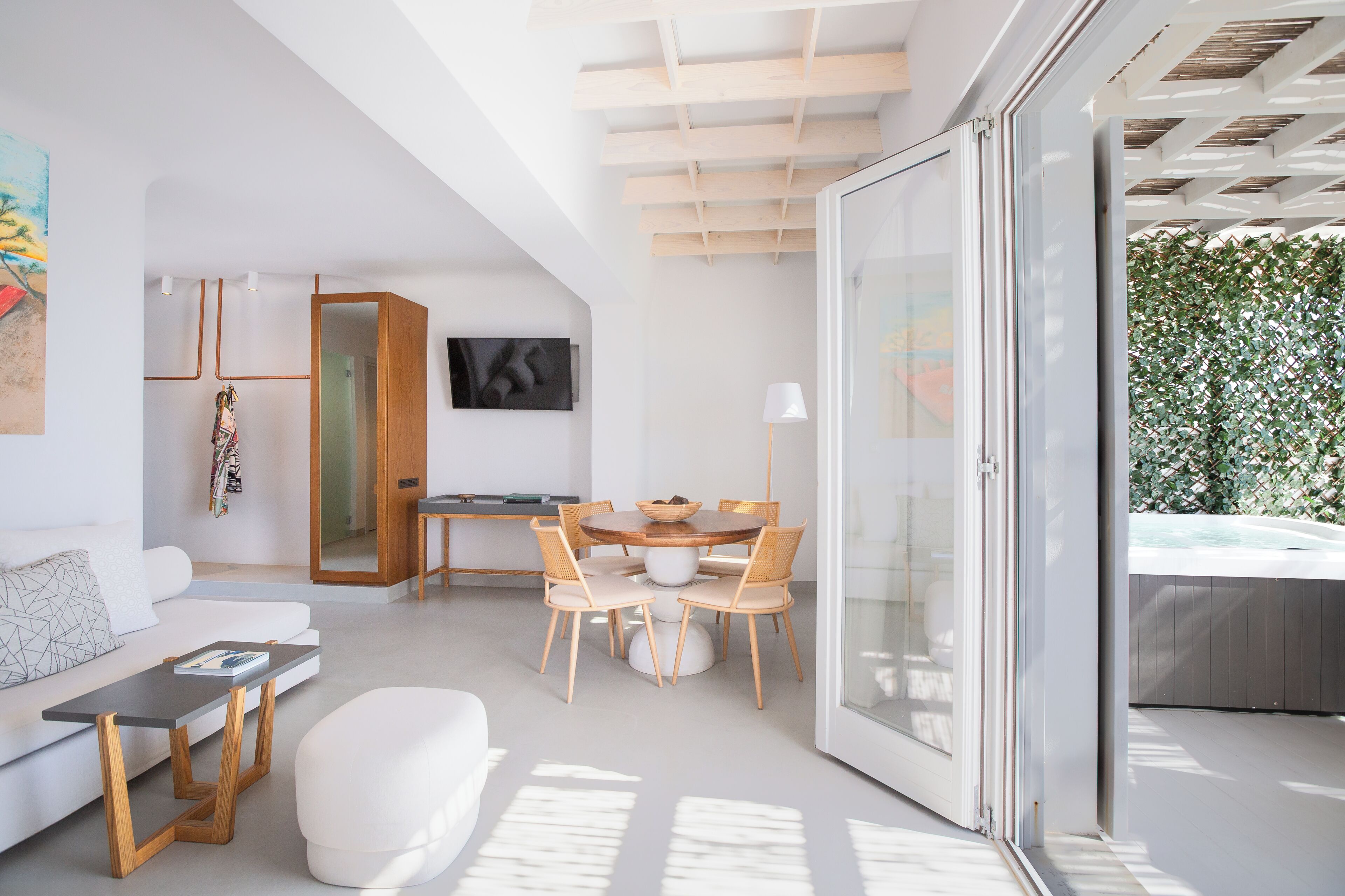 Um interior moderno com área de jantar, sofá, televisão e porta de vidro deslizante para um jardim.