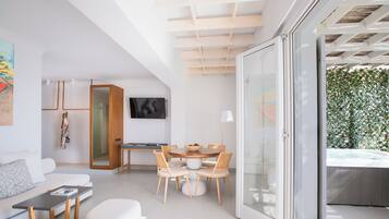 Um interior moderno com área de jantar, sofá, televisão e porta de vidro deslizante para um jardim.