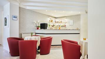 Uma área de bar moderna com balcão branco, cadeiras vermelhas e seleção de garrafas.
