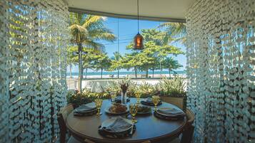 Mesa de jantar posta para quatro com vista para o oceano e palmeiras.