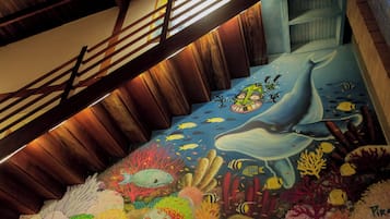 Uma escadaria com um mural que retrata uma cena subaquática, incluindo uma baleia, peixes e corais.