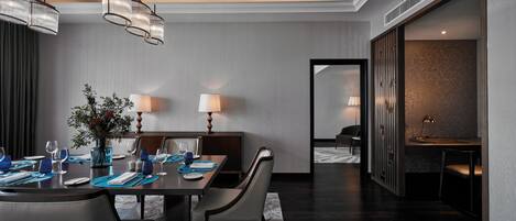 Uma sala de jantar moderna com uma mesa de madeira escura posta para quatro pessoas, jogos americanos azuis e duas luminárias.