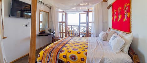 Quarto com cama, televisão, espelho e janela com vista.