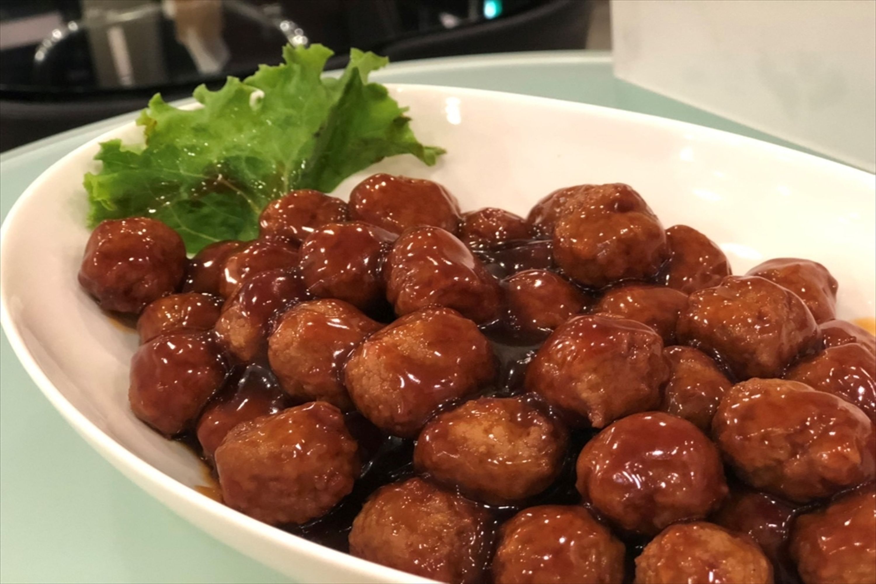 Uma tigela de almôndegas glaceadas com uma salada.