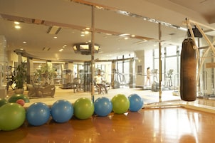 Uma academia com equipamentos de ginástica, um saco de pancada e bolas de exercício.