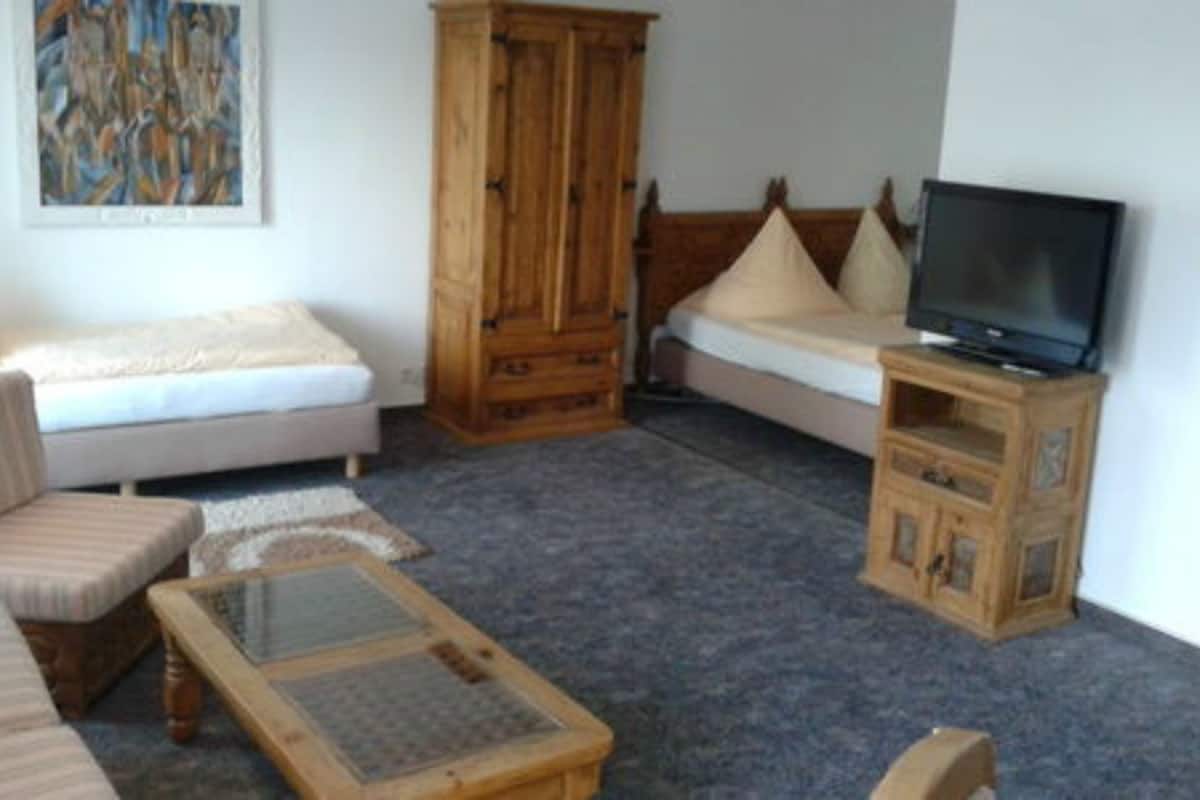Um quarto pequeno e acolhedor com sofá, cama, televisão e armário.