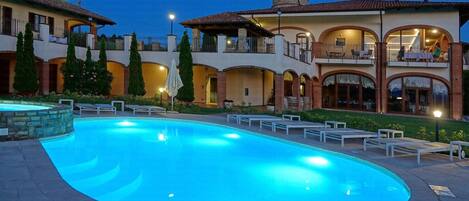 Piscina com espreguiçadeiras, um alpendre coberto e uma área de restaurante com mesas ao ar livre.