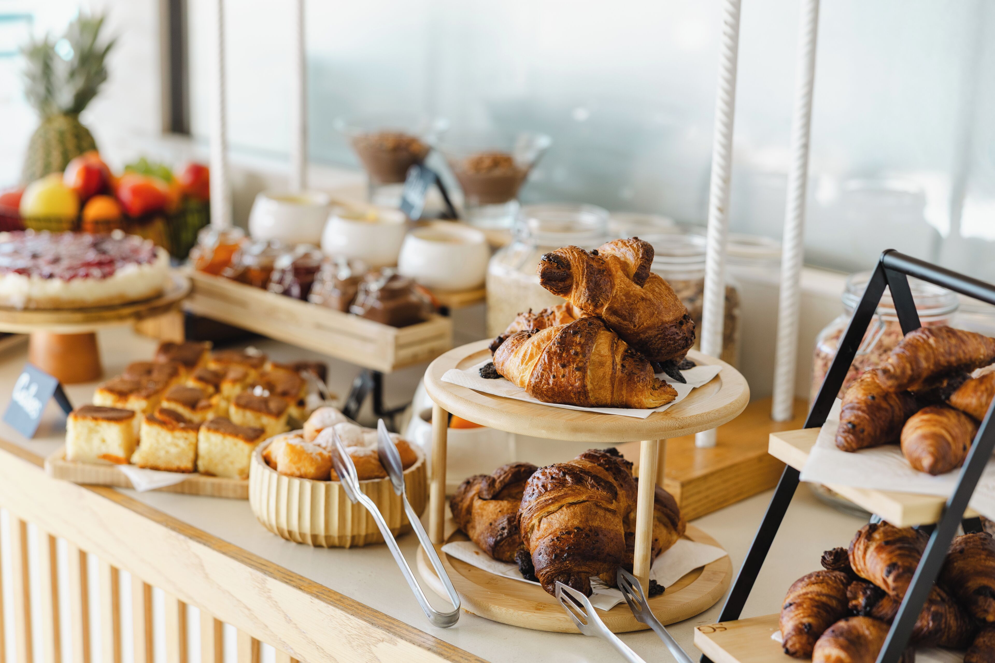 Buffet com diversos pães e frutas.