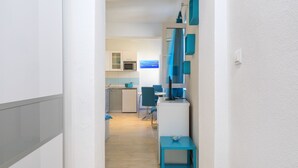 Quarto de hotel moderno com cozinha, mesa de jantar e vista para o mar.