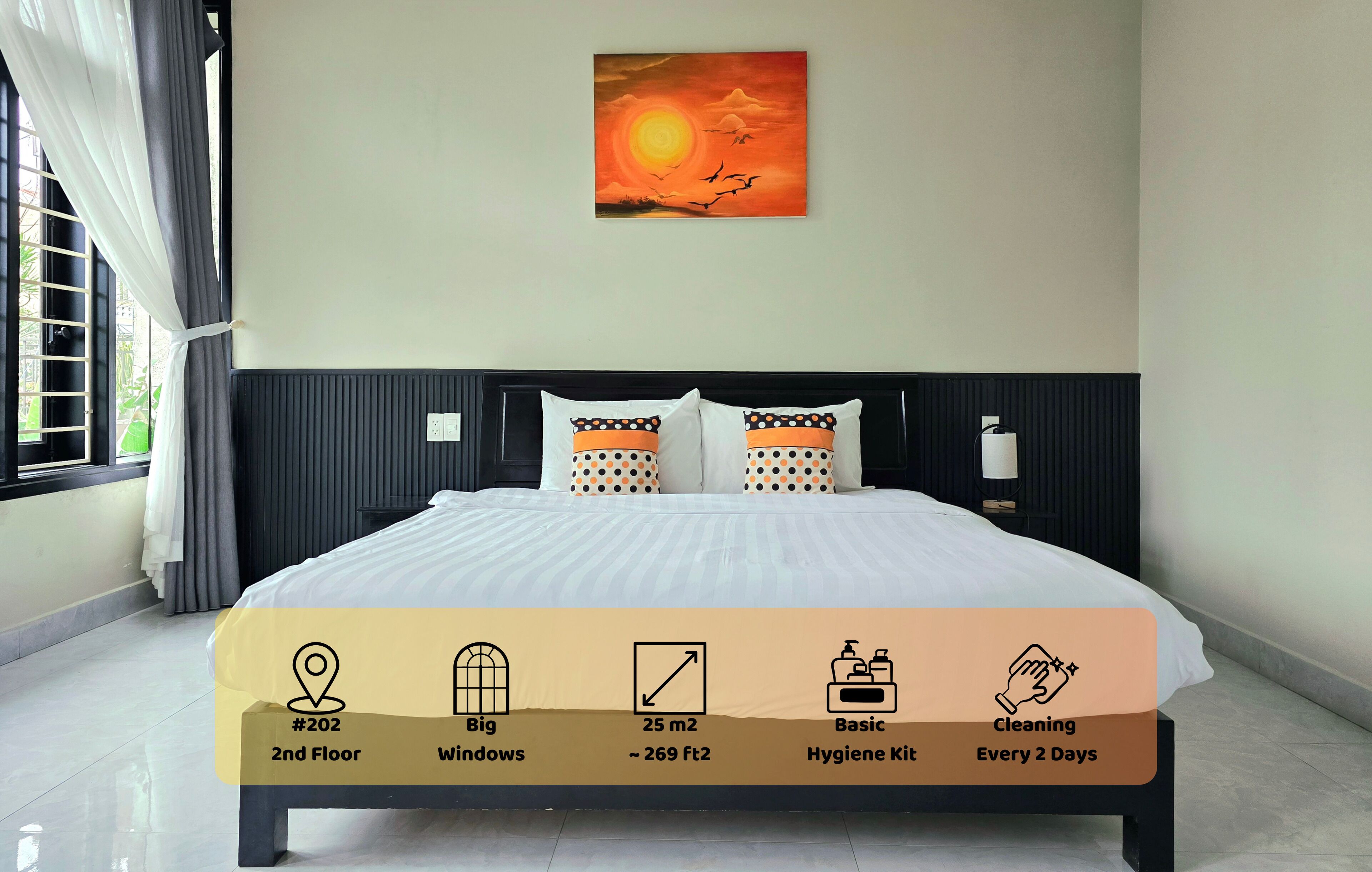 Quarto de hotel com cama, pintura do pôr do sol e janela com cortinas. O quarto oferece kit de higiene básico e instruções de limpeza a cada dois dias.
