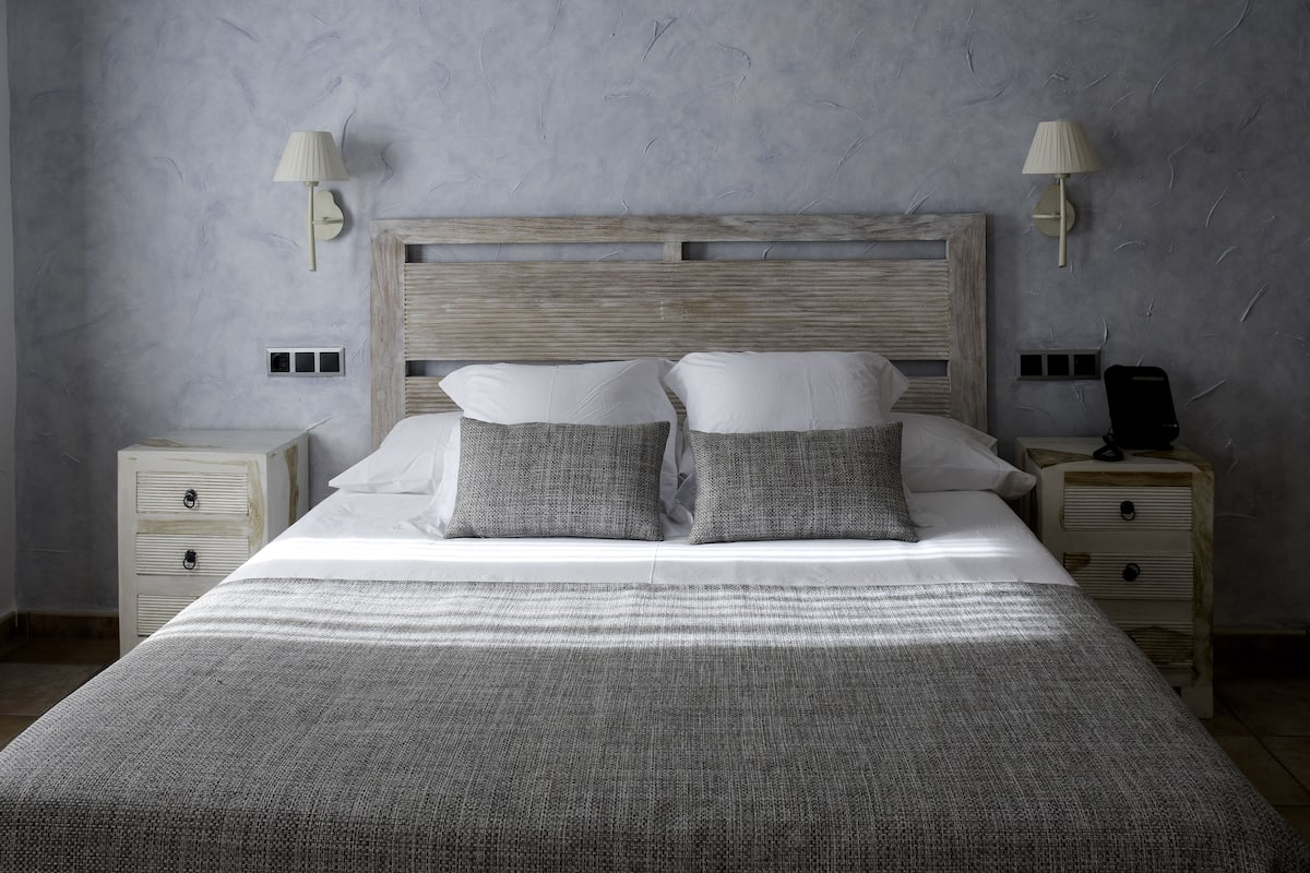 Quarto com uma cama grande, duas mesas de cabeceira e uma cabeceira.