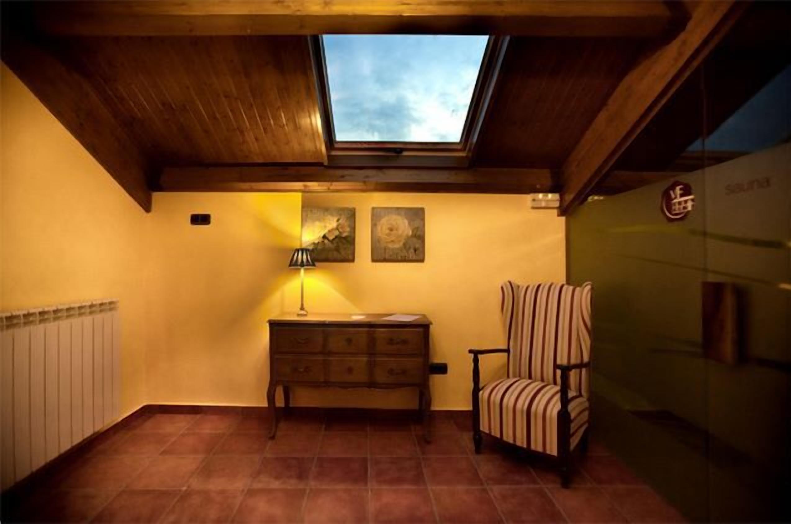 Um quarto de sótão aconchegante com claraboia, radiador, cómoda de madeira, cadeira listrada e placa de sauna.