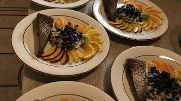 Uma mesa com várias sobremesas, incluindo fatias de bolo, kiwi, laranja e mirtilos.