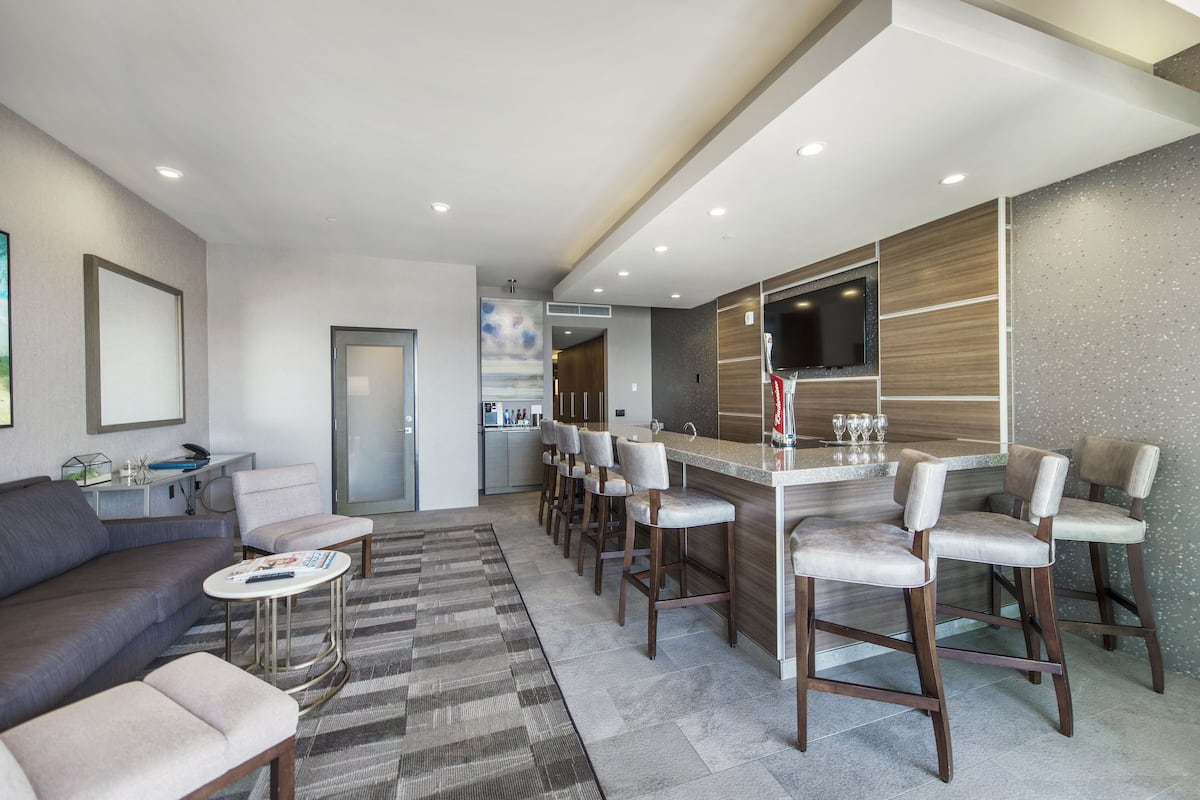 Uma sala de estar moderna com sofá, mesa de centro e área de bar com banquetas.