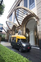 Uma carrinha preta com toldo amarelo estacionada em frente a um edifício com grandes janelas arqueadas e fachada de pedra.