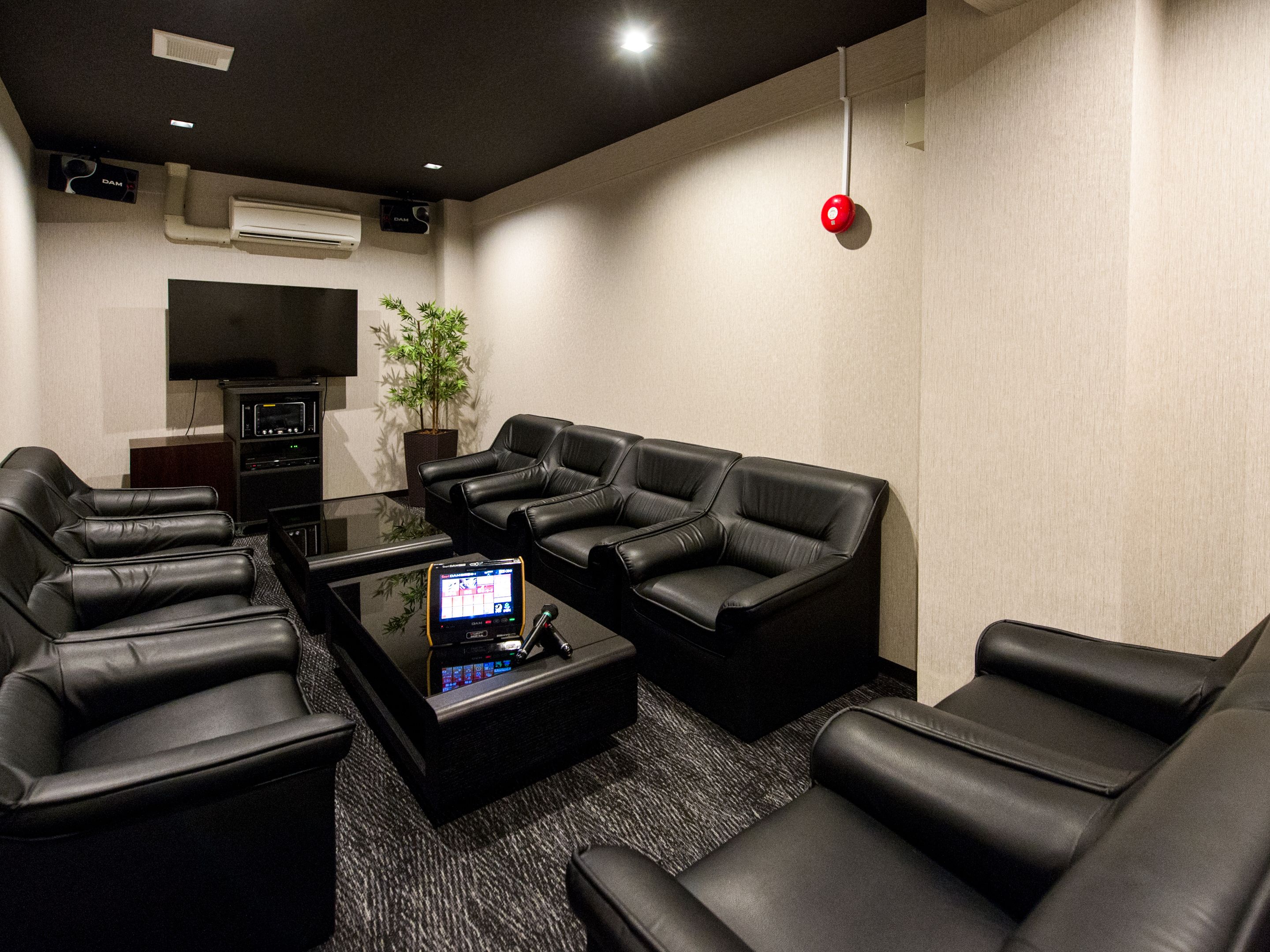 Uma sala de cinema moderna, com sofás de couro, uma TV de tela plana e um sistema de som.