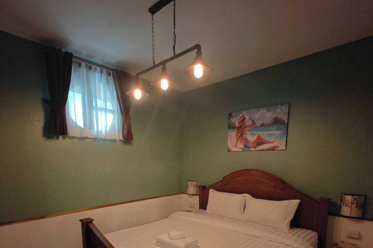 Um quarto com cama, um quadro, uma janela com cortinas e uma mesa de cabeceira.