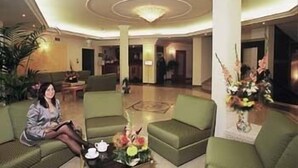 Um hall espaçoso com teto alto, áreas de estar confortáveis e um imponente pilar decorativo.
