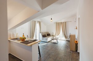 Suíte luxo, vista parcial para o mar | Área de estar | TV LED 32 polegadas com canais a cabo, TV, livros