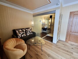 Uma sala de estar moderna com um sofá, uma mesa de centro de vidro e piso de madeira.