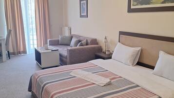 Quarto de hotel com uma cama grande, um sofá, uma escrivaninha e uma cadeira.