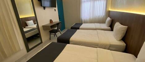Quarto de hotel com duas camas, uma escrivaninha, uma cadeira, televisão na parede e janela com cortinas.