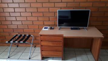 Uma mesa com uma televisão, um pequeno aparelho e uma cadeira.