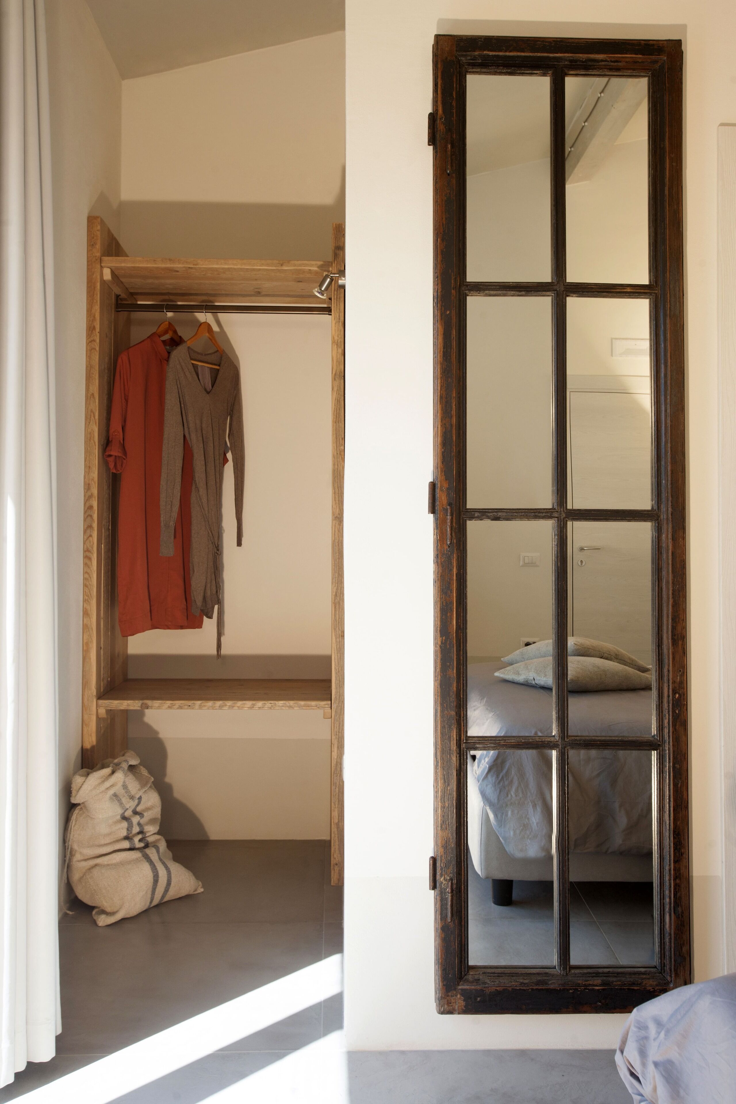Quarto com guarda-roupa de madeira, espelho e cama.