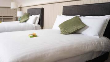 Quarto de hotel com duas camas, cada uma com cabeceira escura e roupa de cama branca.