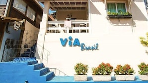 A building with a sign reading "VIA Brasil" and a balcony with a person standing.