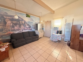 Uma sala de estar com sofá, mesa com cafeteira e um mural na parede.