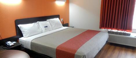 Quarto de hotel com cama, mesa de cabeceira e uma cadeira.