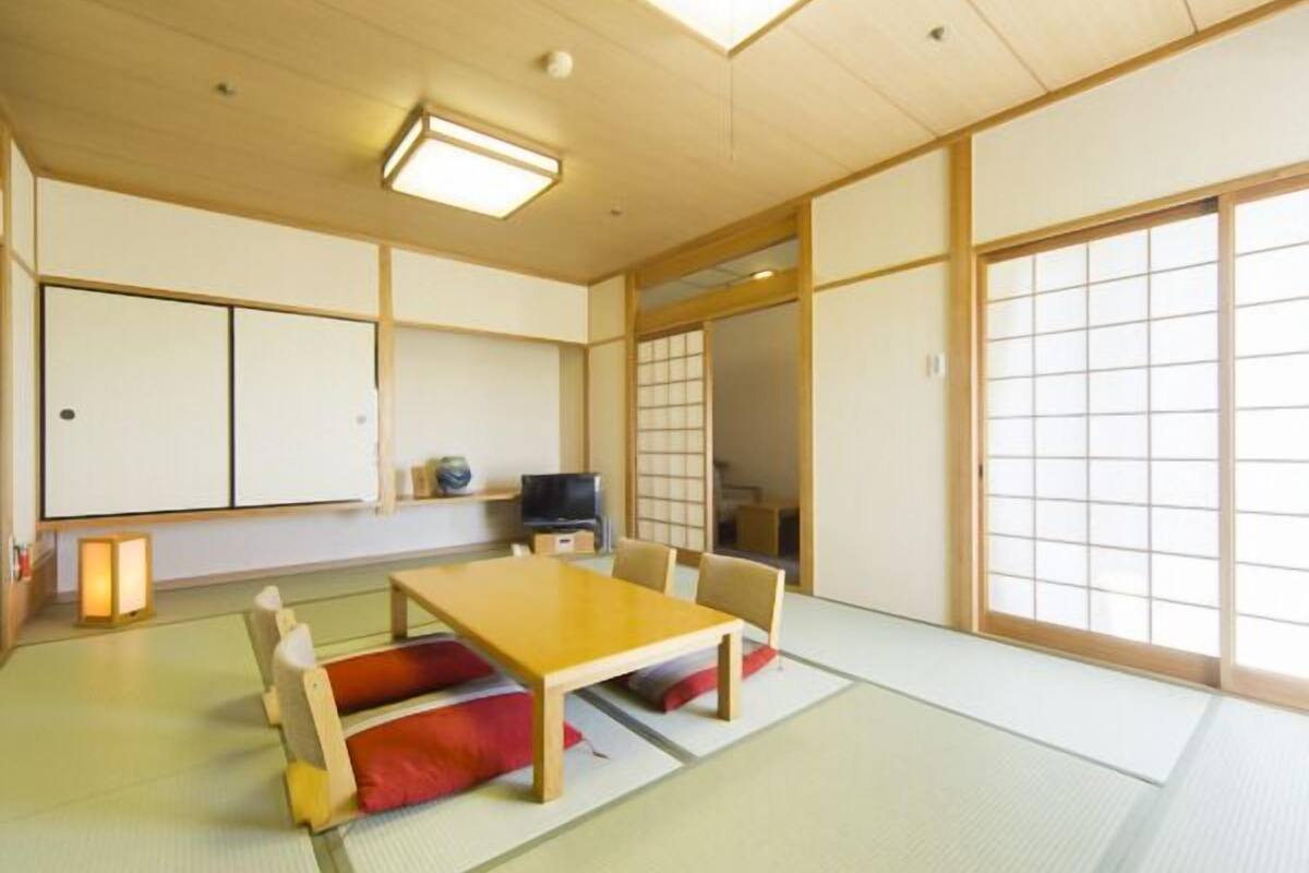 Um quarto japonês tradicional com tatames, uma mesa de madeira baixa e portas deslizantes shoji.