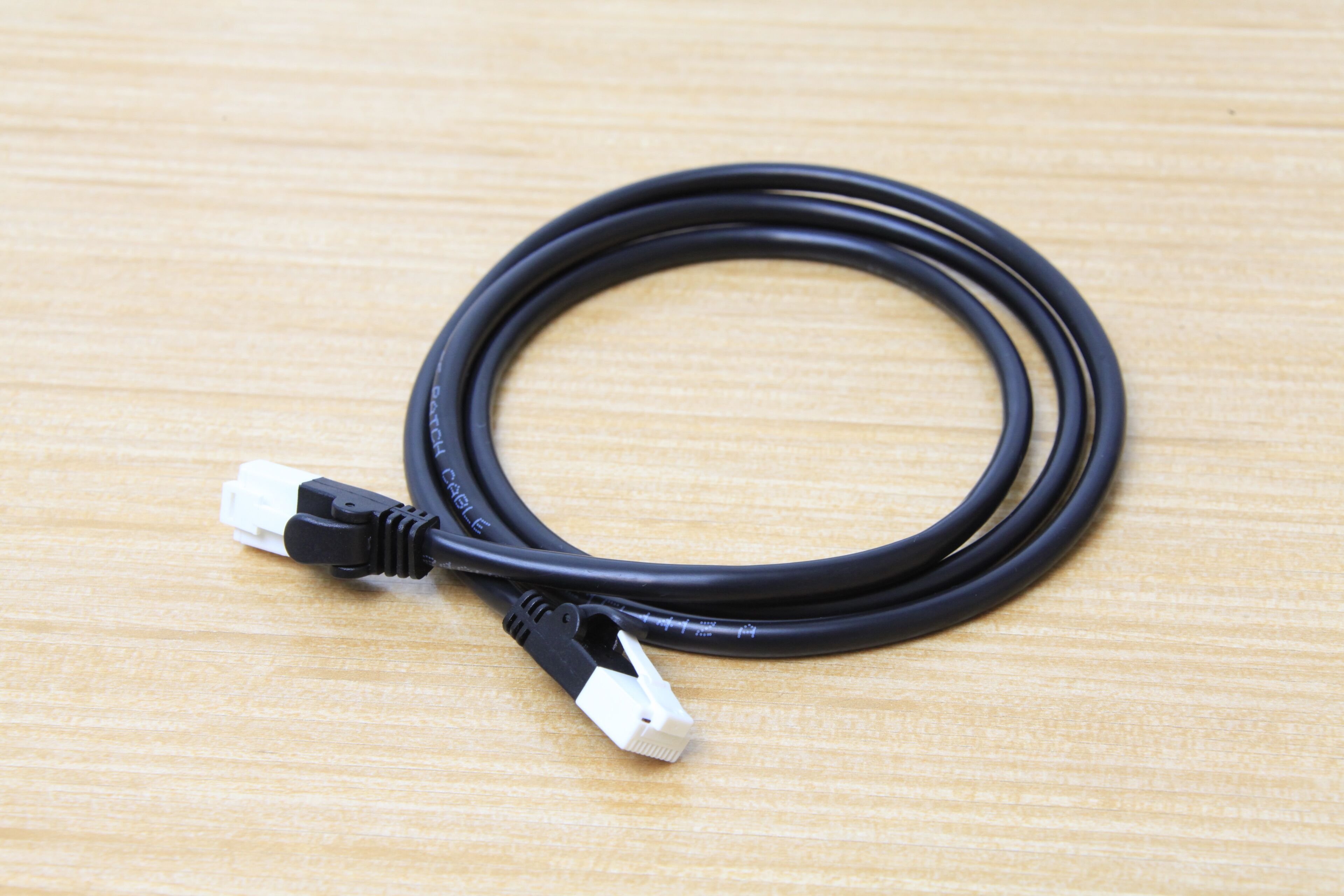Um cabo preto com um conector branco sobre uma superfície de madeira.