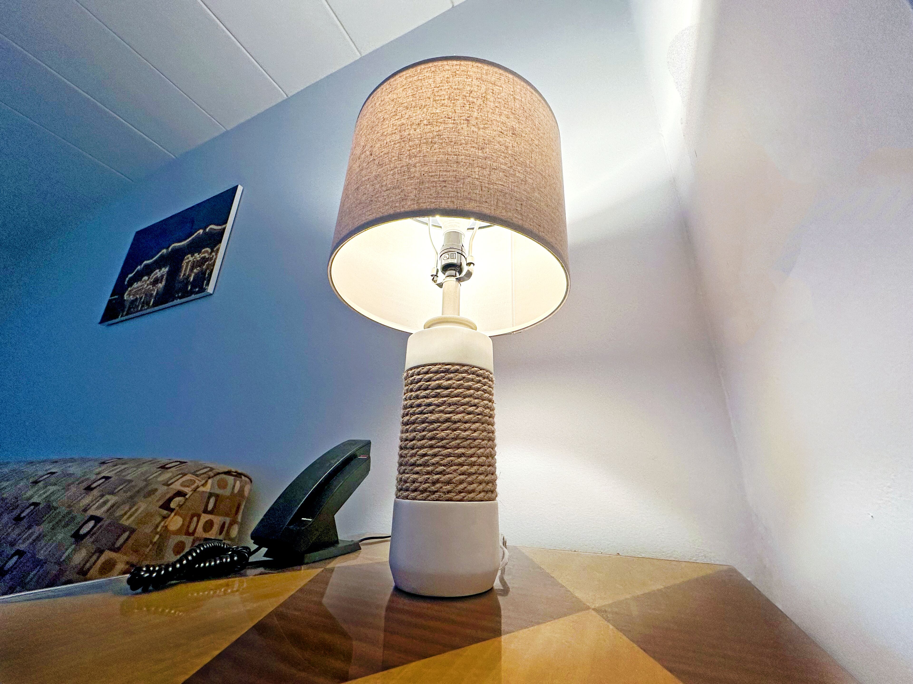 Luminária com base texturizada e cúpula grande e arredondada sobre uma mesa de madeira.