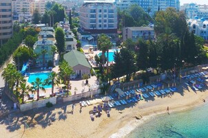 Vista aérea de um resort à beira-mar, com piscina, praia e vários edifícios.