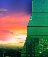 Um edifício moderno de arranha-céus com fachada de vidro, com o céu ao fundo durante o pôr do sol.